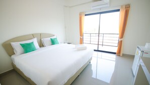 Quarto de hotel com cama grande, escrivaninha e janela com cortinas.