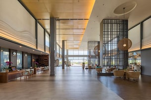 Um hall amplo com balcão de recepção, áreas de estar e uma grande janela com vista para o exterior.
