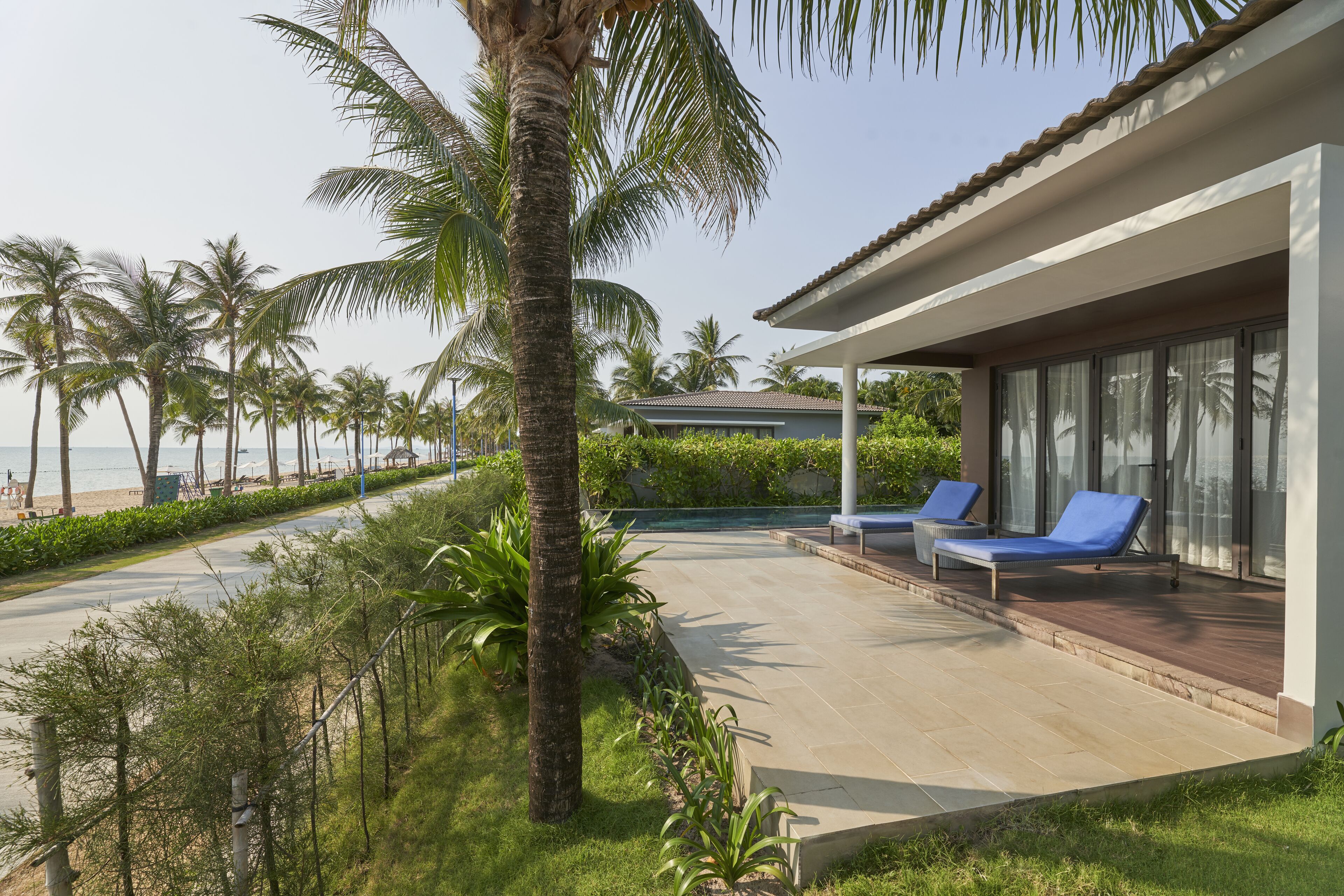 Um resort moderno com área de piscina, palmeiras e vista para a praia.