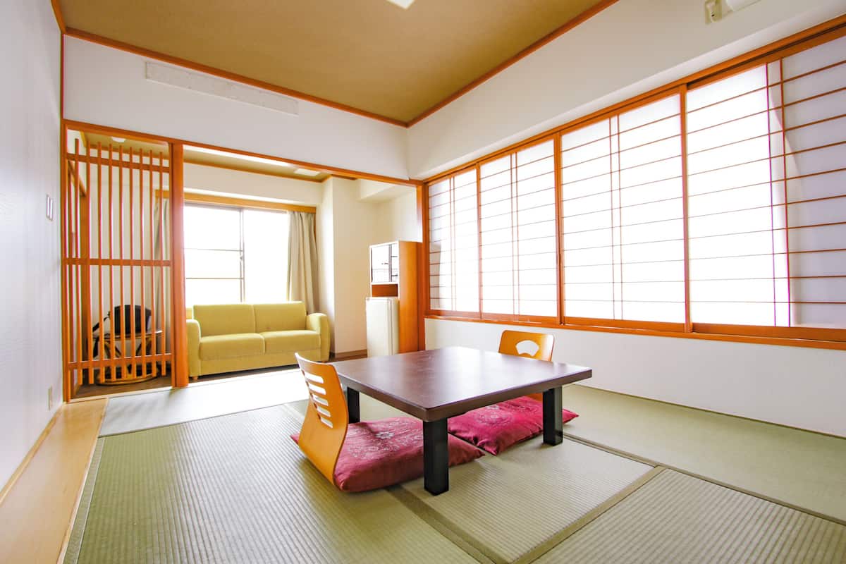 Um quarto japonês tradicional com piso de tatame, uma mesa baixa e portas deslizantes.