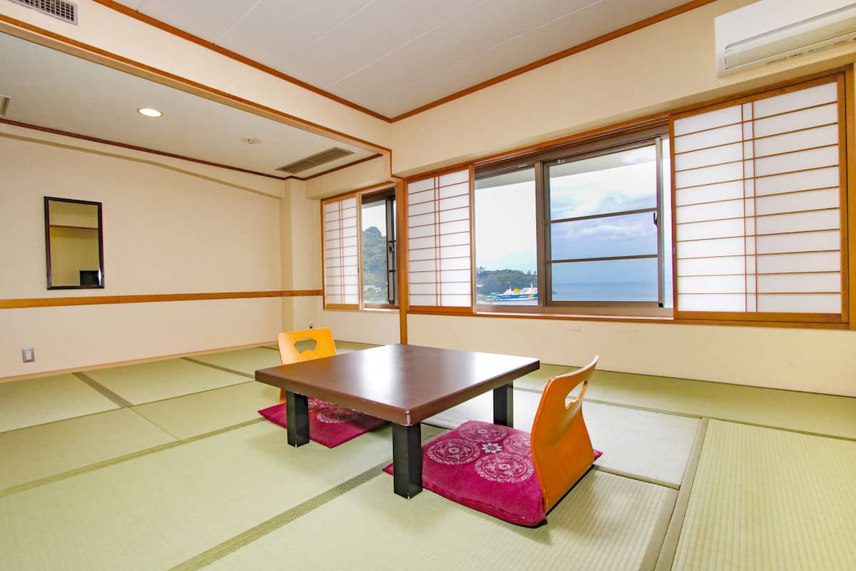 Um quarto japonês tradicional com tatames, uma mesa baixa e portas deslizantes shoji.