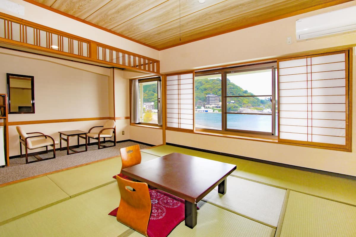 Um quarto japonês tradicional com tatames, uma mesa baixa e cadeiras.