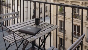 Uma varanda com uma mesa de madeira, um laptop e um vaso de planta.