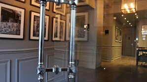Um corredor com quadros nas paredes, piso de madeira polida e um lustre moderno.