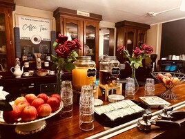 Um canto com café, um cardápio, potes com bebidas e uma tigela de maçãs.