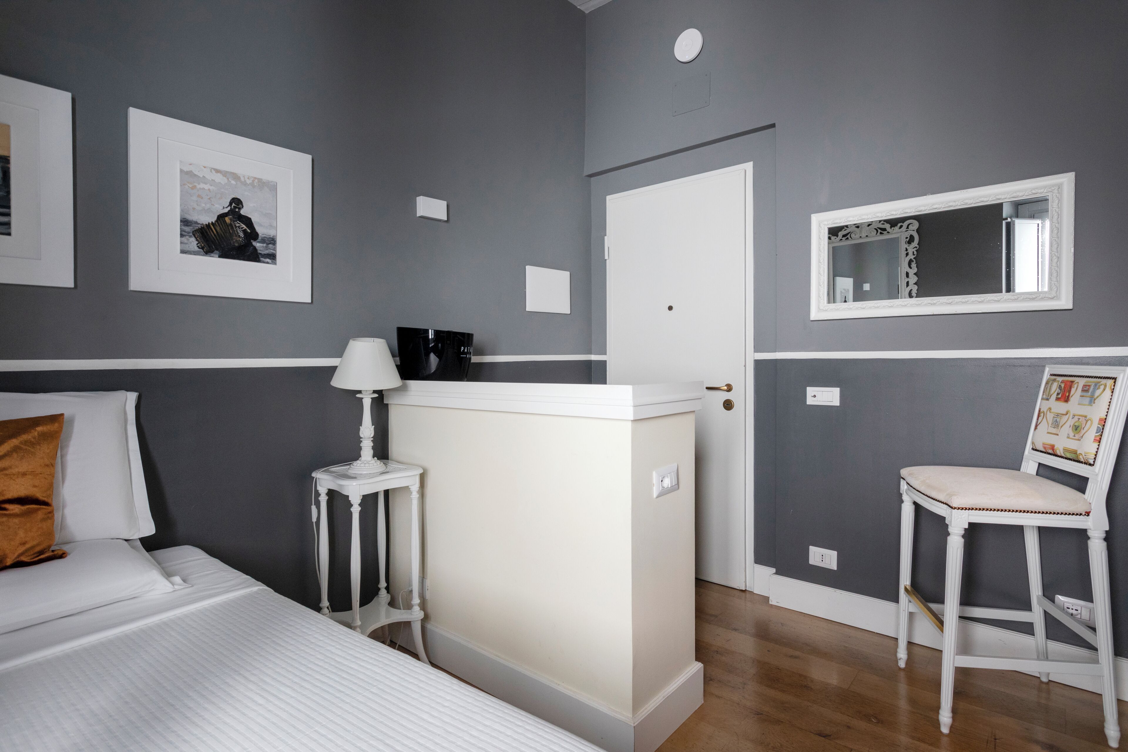 Quarto com cama, mesa de cabeceira, cómoda, cadeira e um quadro na parede.