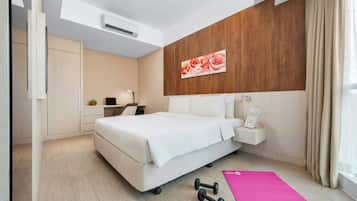 Quarto de hotel moderno com cama, escrivaninha, cadeira, uma pequena planta, moldura de quadro e tapete de exercícios rosa.
