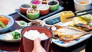 Uma refeição tradicional japonesa com arroz, peixe e acompanhamentos diversos.