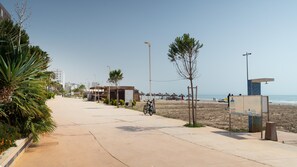 Um calçadão costeiro com uma praia, uma estrutura de madeira e uma torre salva-vidas.
