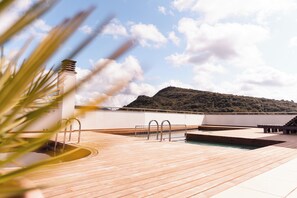 Um deck de madeira com piscina, placa de proibido fumar e montanha ao fundo.