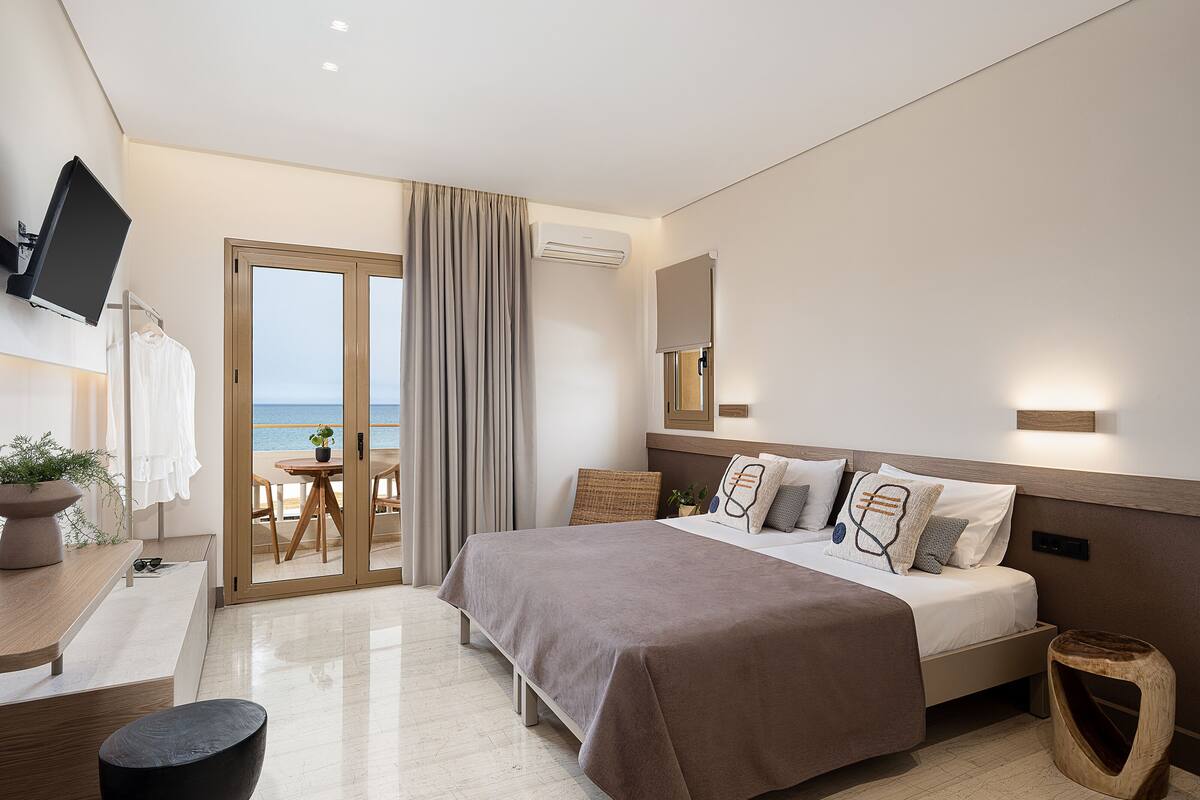 Quarto de hotel moderno com cama, escrivaninha e vista para o mar.