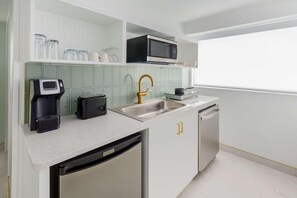 Uma cozinha moderna com micro-ondas, cafeteira e máquina de lavar loiça.