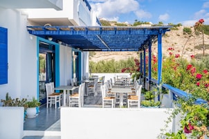 Terraço com área de estar ao ar livre, paredes brancas e detalhes em azul.