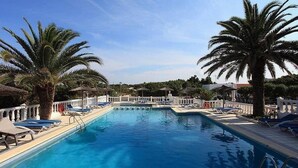 Piscina com espreguiçadeiras e palmeiras.