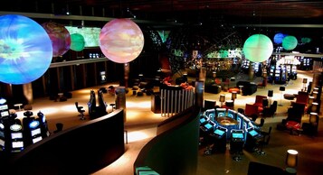 Um interior moderno com máquinas de jogos, áreas de estar e grandes esferas iluminadas.