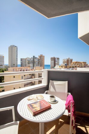 Uma varanda com mesa, cadeira, um livro e uma xícara.