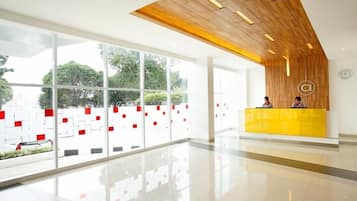 Uma área de recepção moderna com teto de madeira, janelas amplas e balcão de recepção amarelo.
