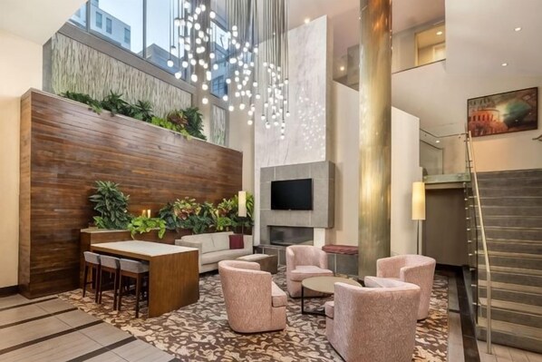 Um lobby moderno com área de estar, televisão de tela plana e escada.