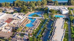 Vista aérea de um resort com uma grande piscina, várias áreas de estar e localização à beira-mar.