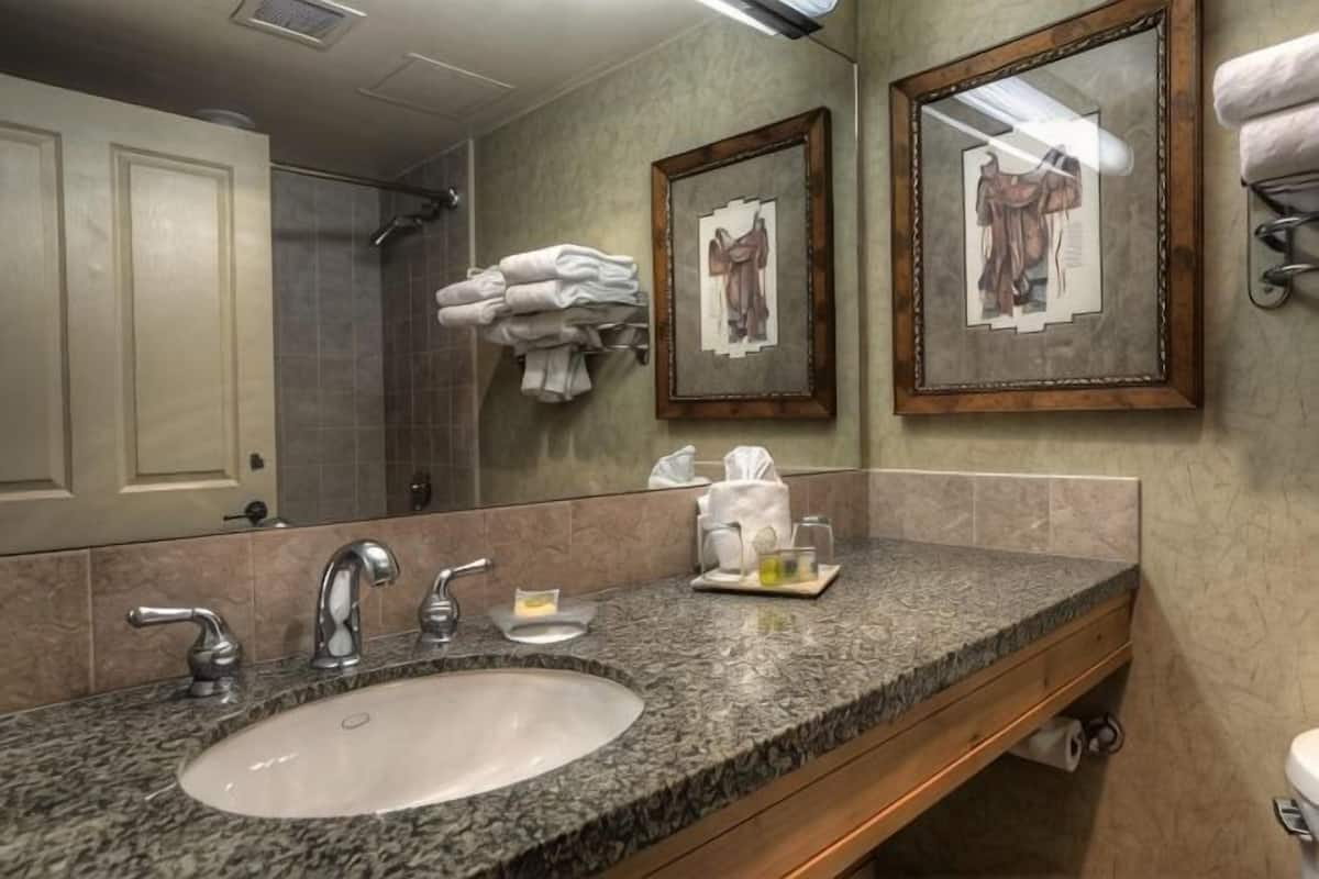 Uma casa de banho com lavatório, espelhos, toalhas e um quadro emoldurado na parede.