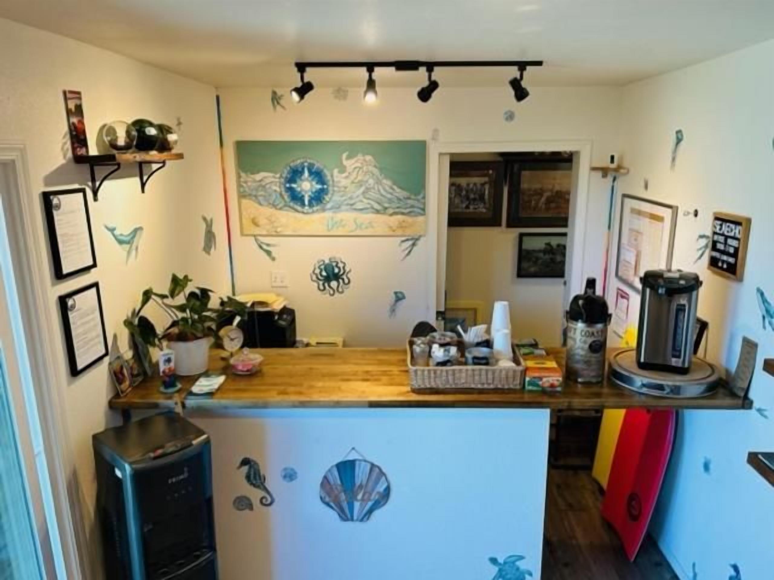 Cozinha compacta com bancada de madeira, cafeteira e diversos utensílios de cozinha.
