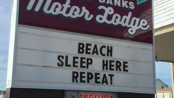 Placa do Outer Banks Motor Lodge anunciando uma noite na praia.