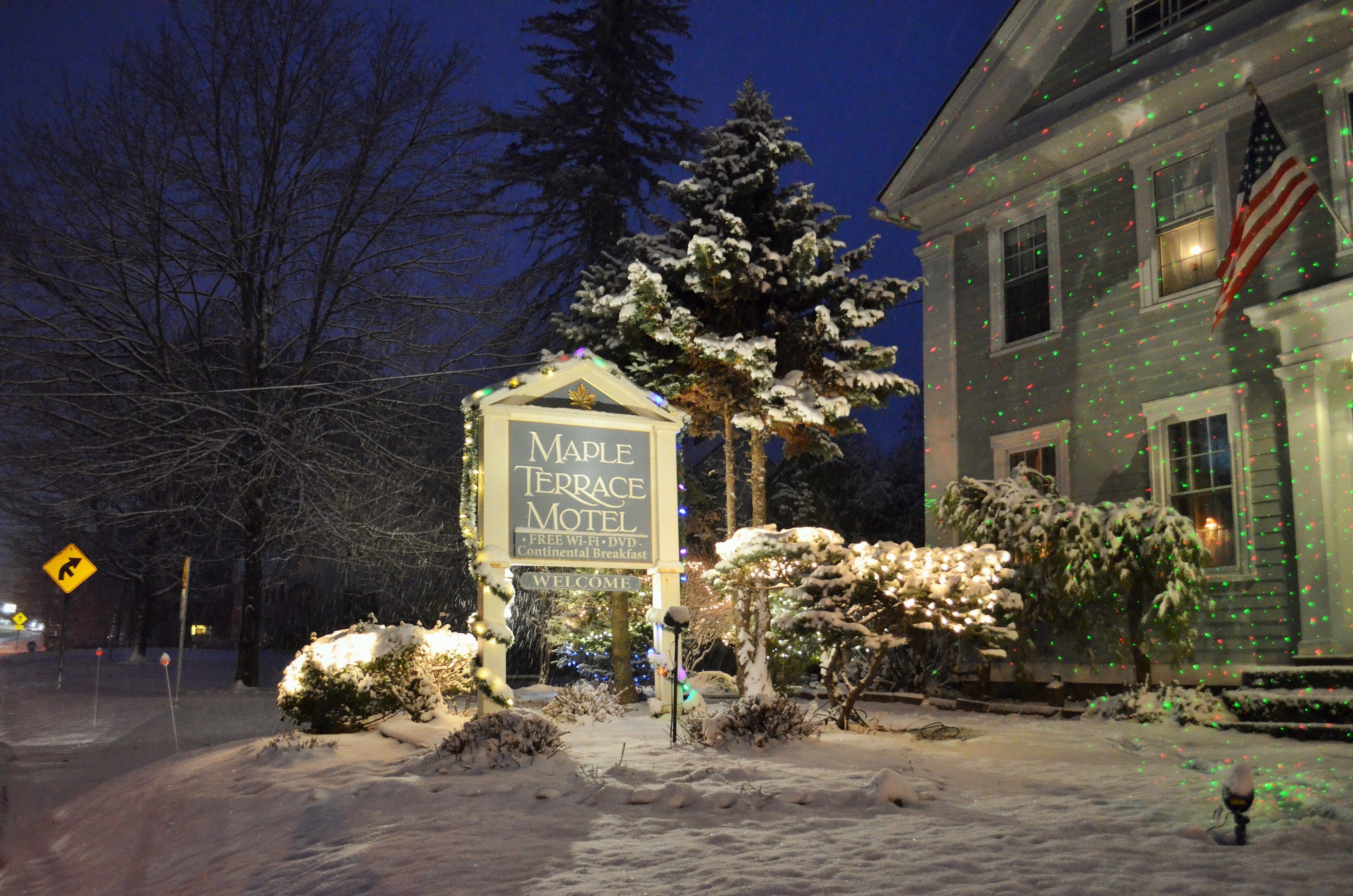 Placa coberta de neve do Motel Maple Terrace, com uma mensagem acolhedora e lista de comodidades.
