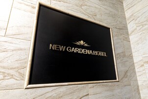 Uma placa preta com letras douradas do Hotel New Gardenah.