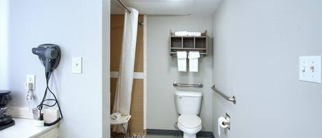 Um banheiro pequeno e limpo, com vaso sanitário, porta-toalhas, cortina de chuveiro e secador de cabelo em uma bancada.