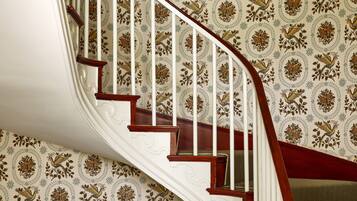 Escadaria em espiral com papel de parede decorado com padrão de flores e pássaros.