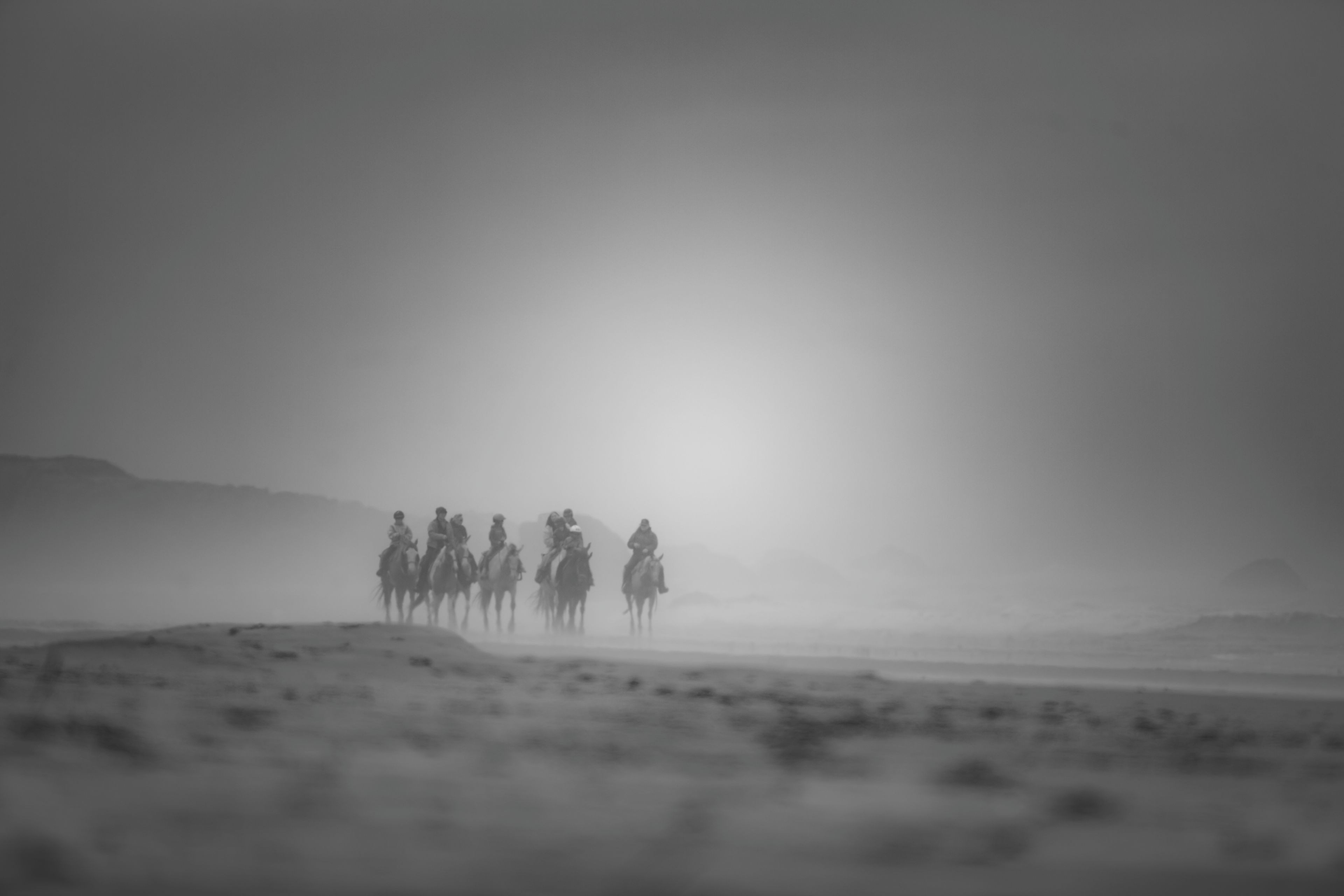 Um grupo de pessoas a cavalo em uma paisagem nevoenta.