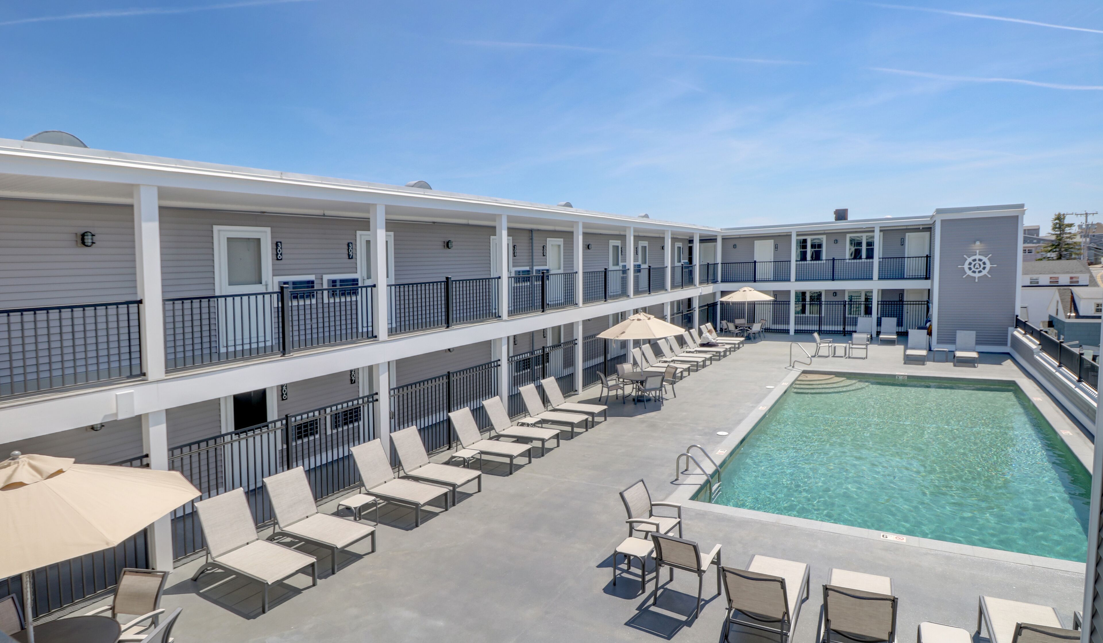Um hotel com área de piscina, várias varandas e espaço para sentar ao ar livre.