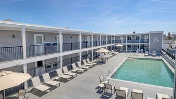 Um hotel com área de piscina, várias varandas e espaço para sentar ao ar livre.