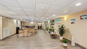 Um hall amplo com balcão de recepção, plantas em vasos e piso ladrilhado.