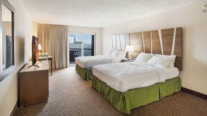 Quarto de hotel com duas camas, uma mesa, uma cadeira, uma janela com cortinas e vista para o exterior.