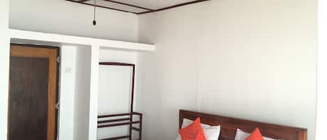 Quarto de hotel com cama, cabeceira de madeira e ventilador de teto.