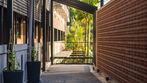 Uma galeria coberta ao ar livre com portão de metal, plantas em vasos e parede de tijolos.
