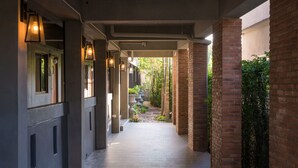Um corredor com colunas de tijolo, plantas em vasos e luminárias pendentes.