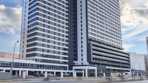 Um edifício alto e moderno, com uma fachada de janelas em grade e telhado plano.