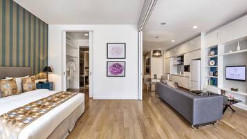 Quarto de hotel moderno com uma cama, um sofá, uma área de refeições e uma televisão.