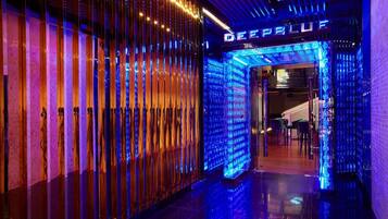 Um interior moderno com uma entrada iluminada em azul e uma placa com a inscrição "DEEPBLUE".