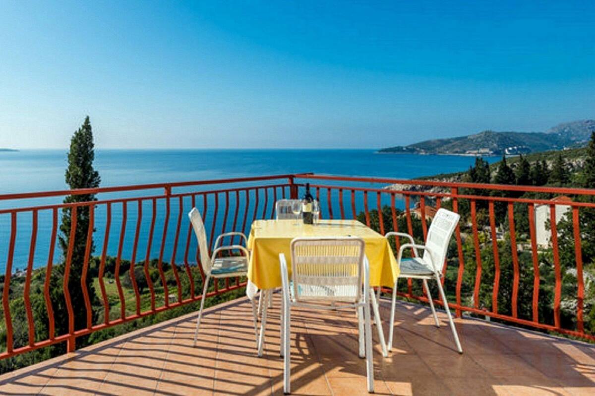 Terraço com mesa e cadeiras com vista para a costa.