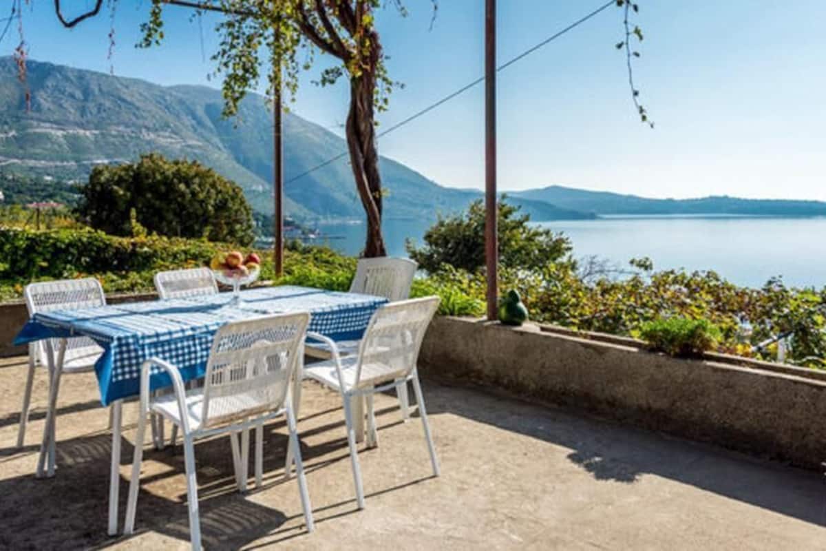 Um terraço com mesa e cadeiras, com vista para um lago e montanhas.