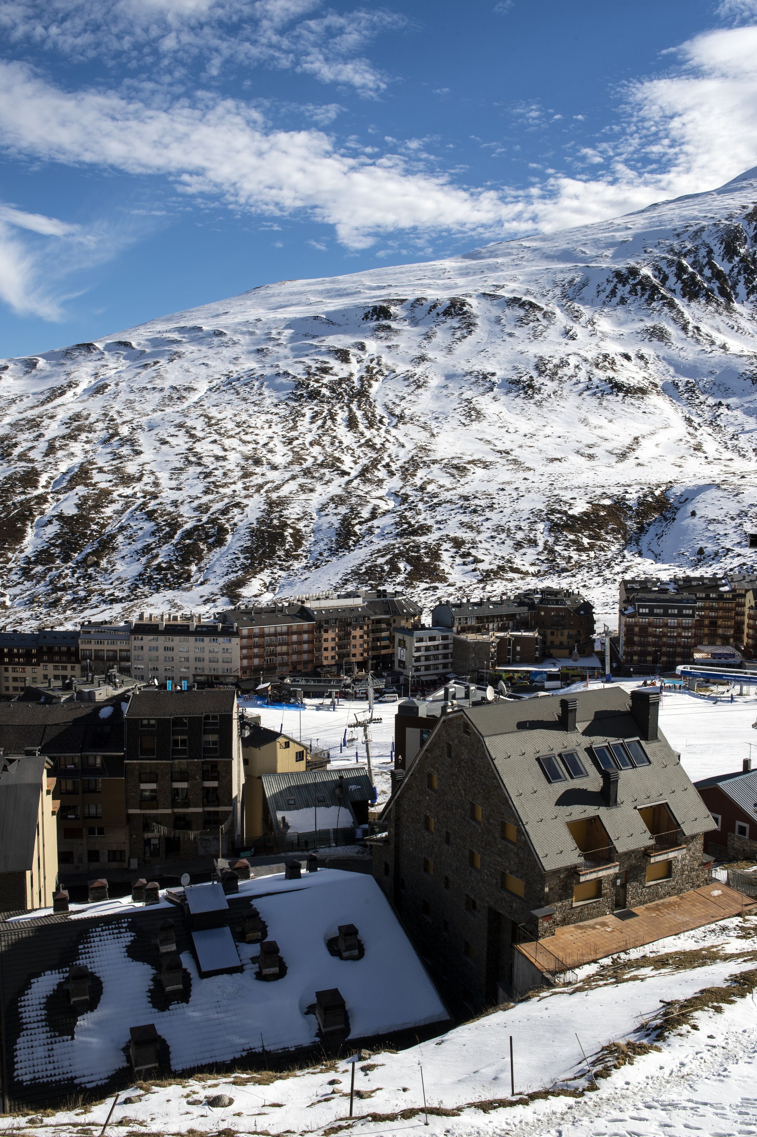 Uma cidade nas montanhas coberta de neve, com edifícios e uma pista de esqui.