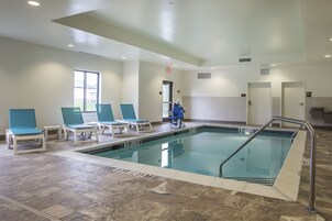 Piscina com espreguiçadeiras, sala de trocas e uma porta com sinal de saída.