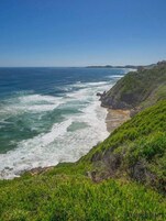 Paisagem costeira com vista para o oceano e um penhasco gramado.