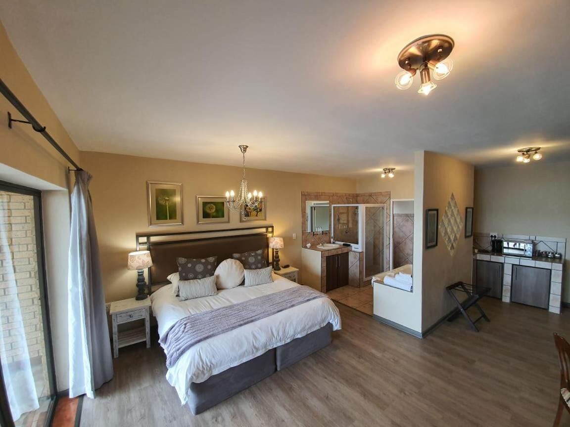 Quarto moderno com uma cama grande, mesas de cabeceira, um criado-mudo, uma escrivaninha e um banheiro.