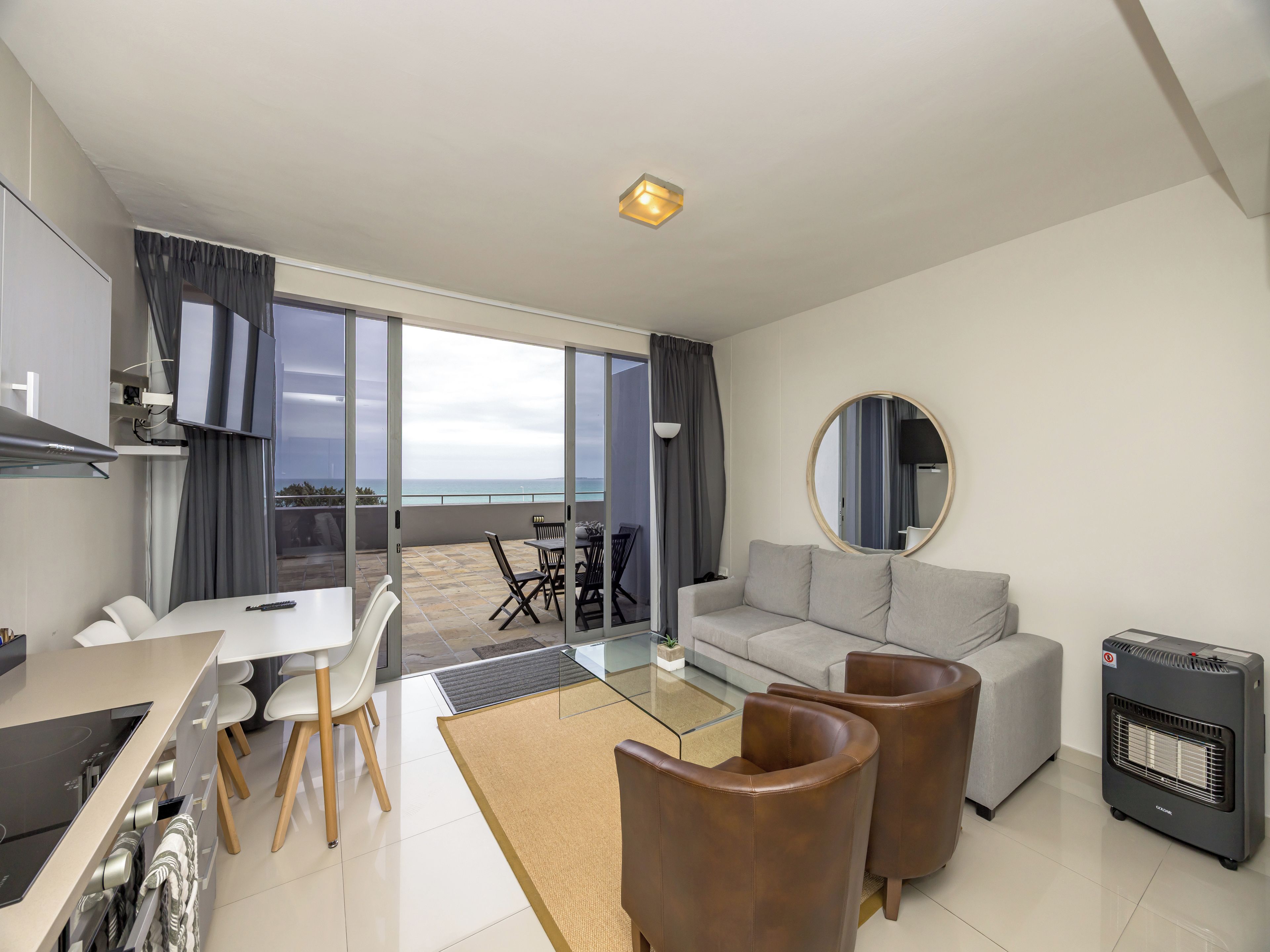 Uma sala de estar moderna com sofá, cadeiras, mesa de jantar e cozinha.