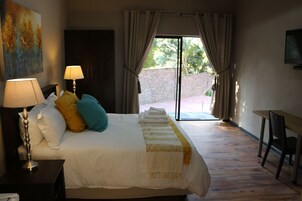 Quarto de hotel com cama, secretária e televisão.