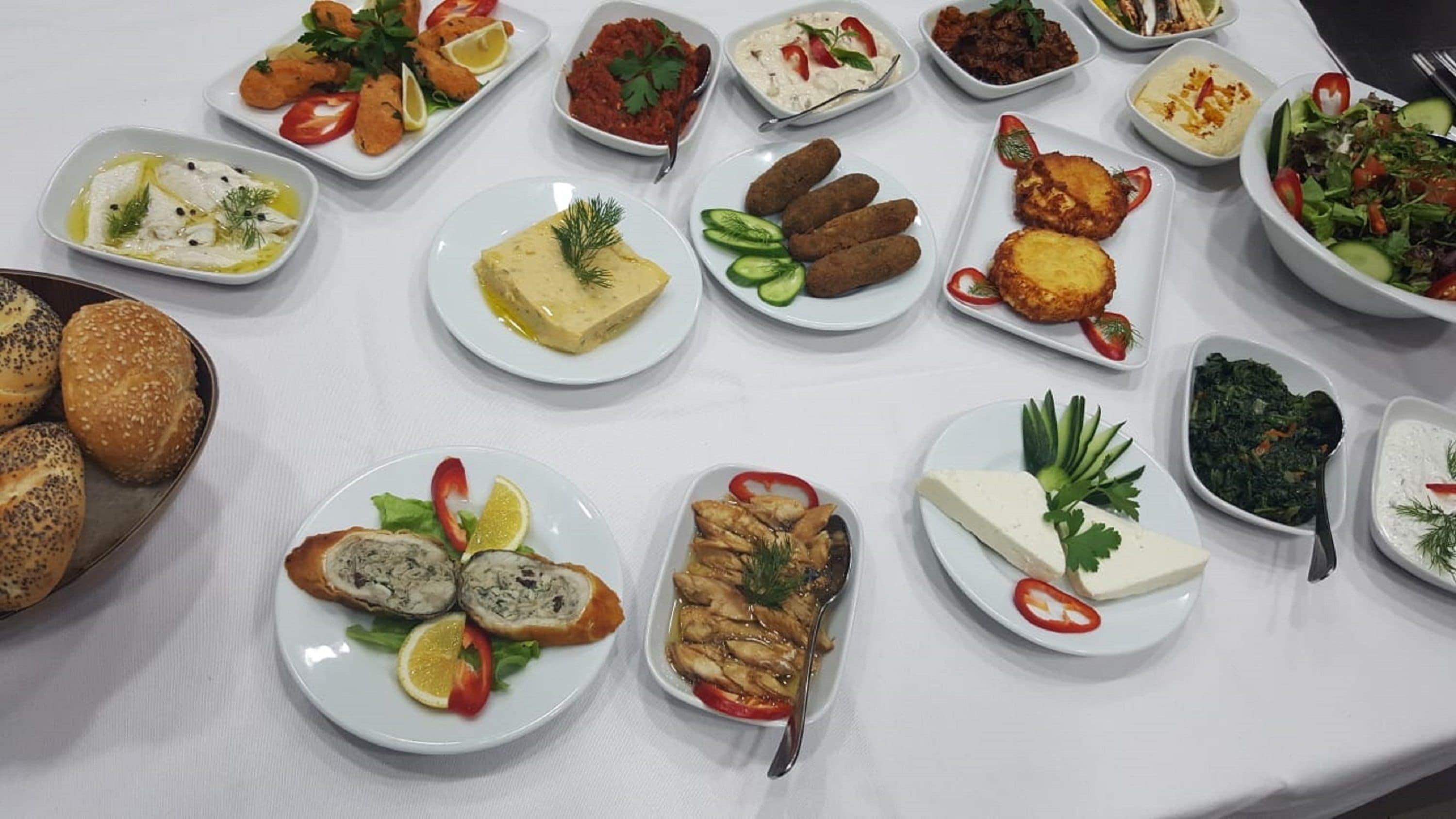 Uma mesa com vários pratos, incluindo peixe, pão e saladas.